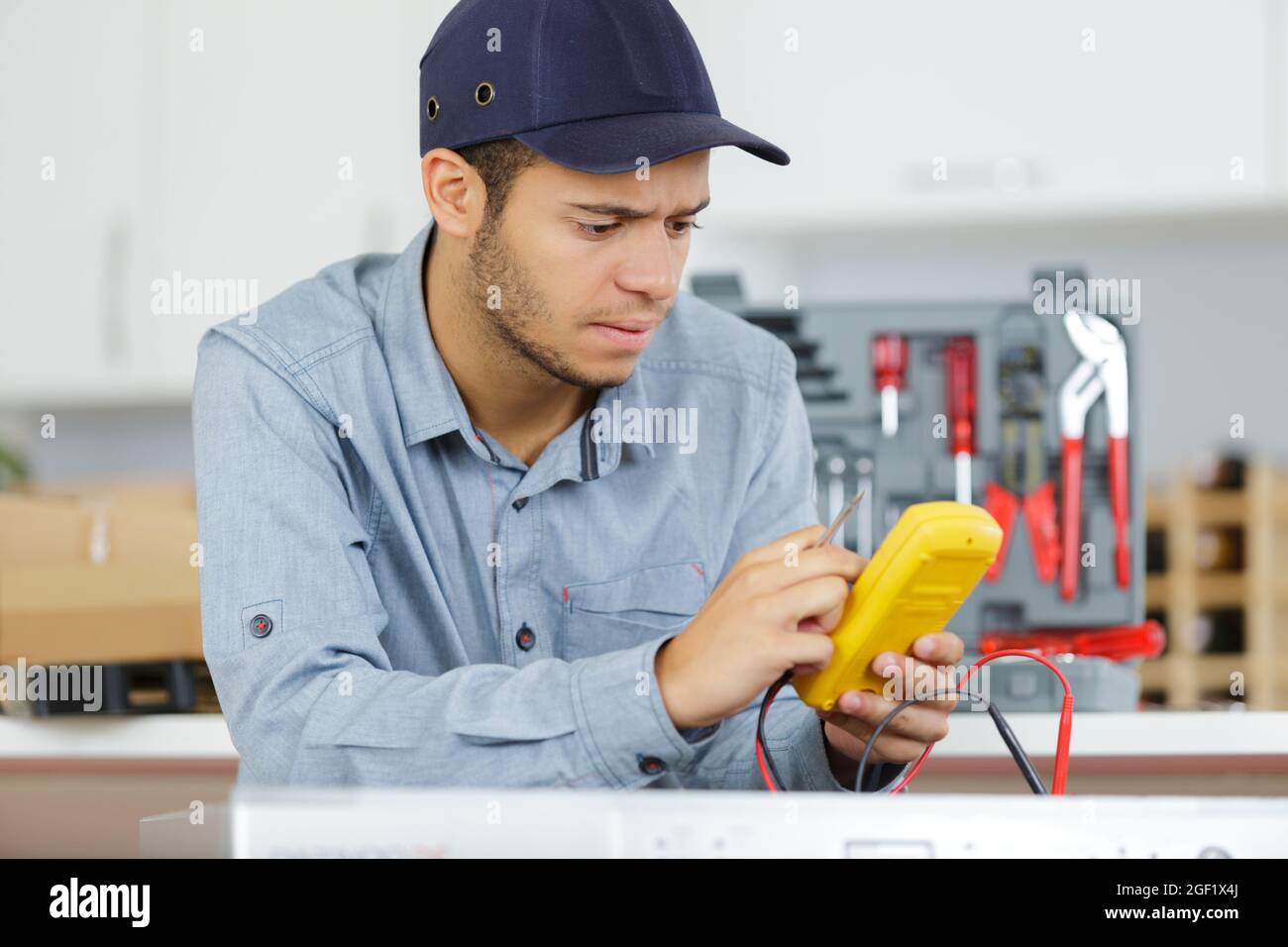serviceman frowning while using multimeter to test appliance Stock ...