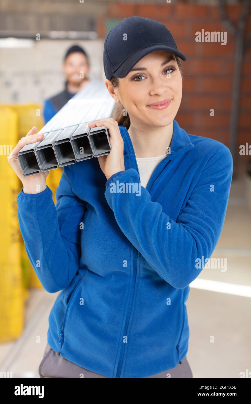 male and female colleagues carrying metal lengths on their shoulders ...