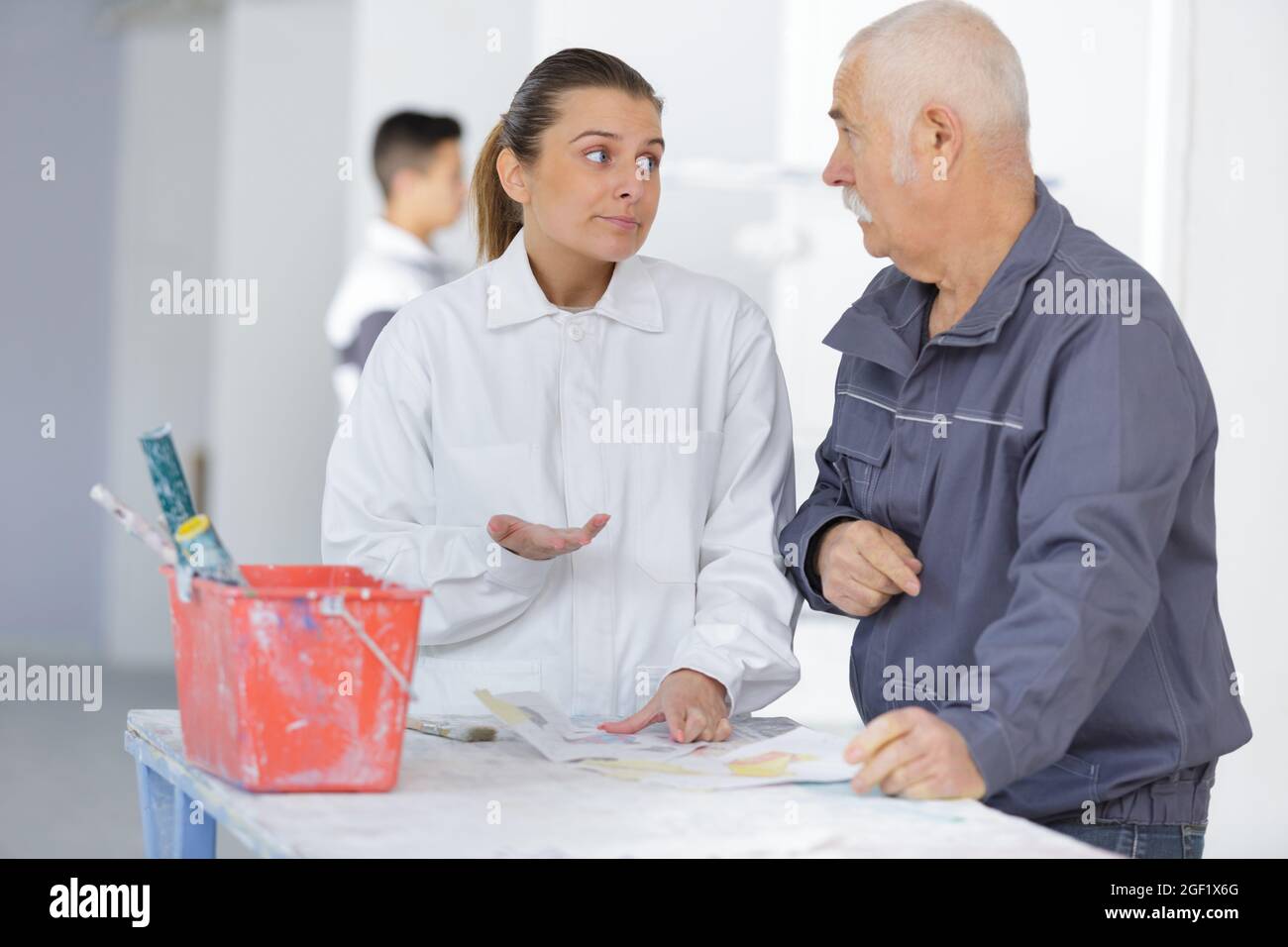 young apprentice painter shrugging while talking to foreman Stock Photo ...