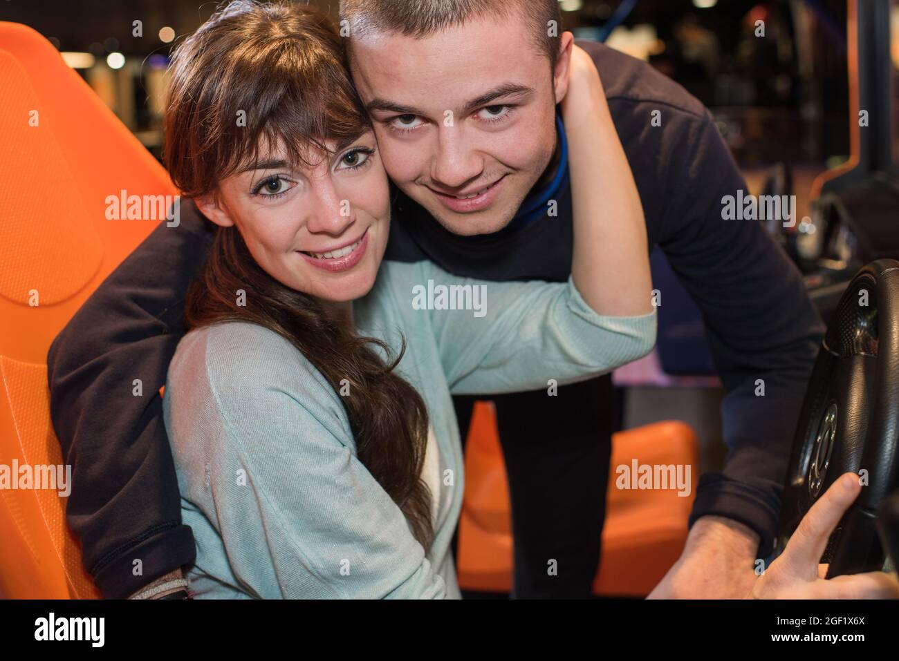 portrait of young couple embracing at arcade driving game Stock Photo ...