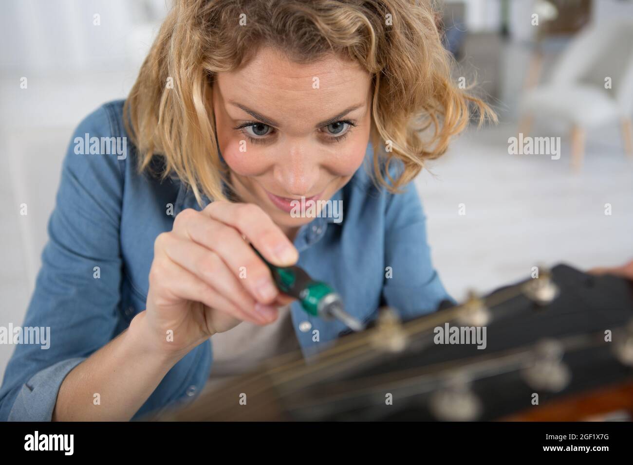 female guitar maker builds string tensioner on new guitar Stock Photo ...