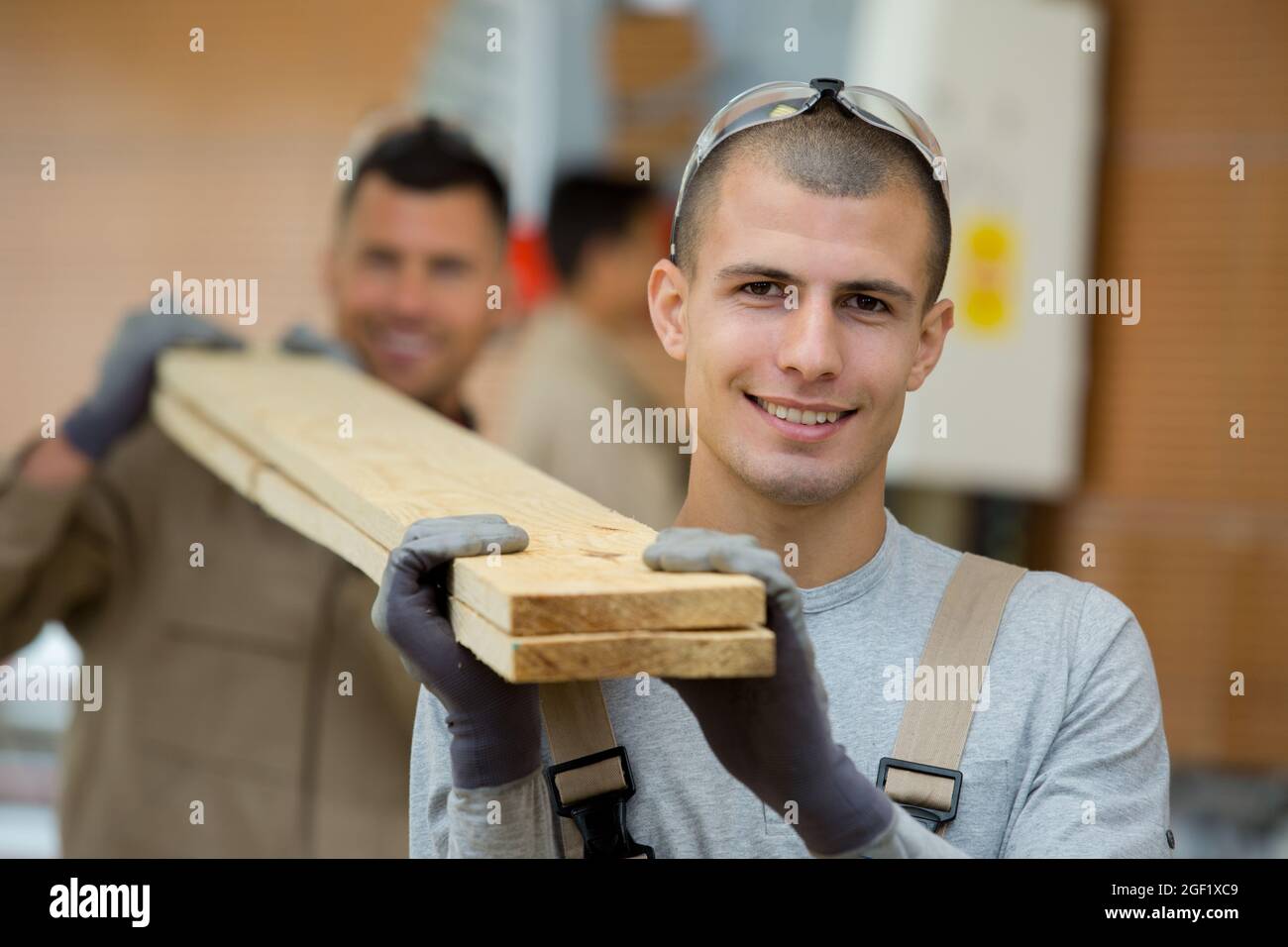 skilled workers carrying wood at construction site Stock Photo - Alamy