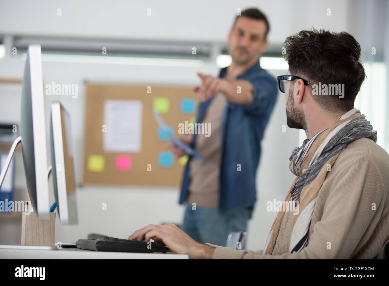 teacher pointing and giving instructions to student using computer ...