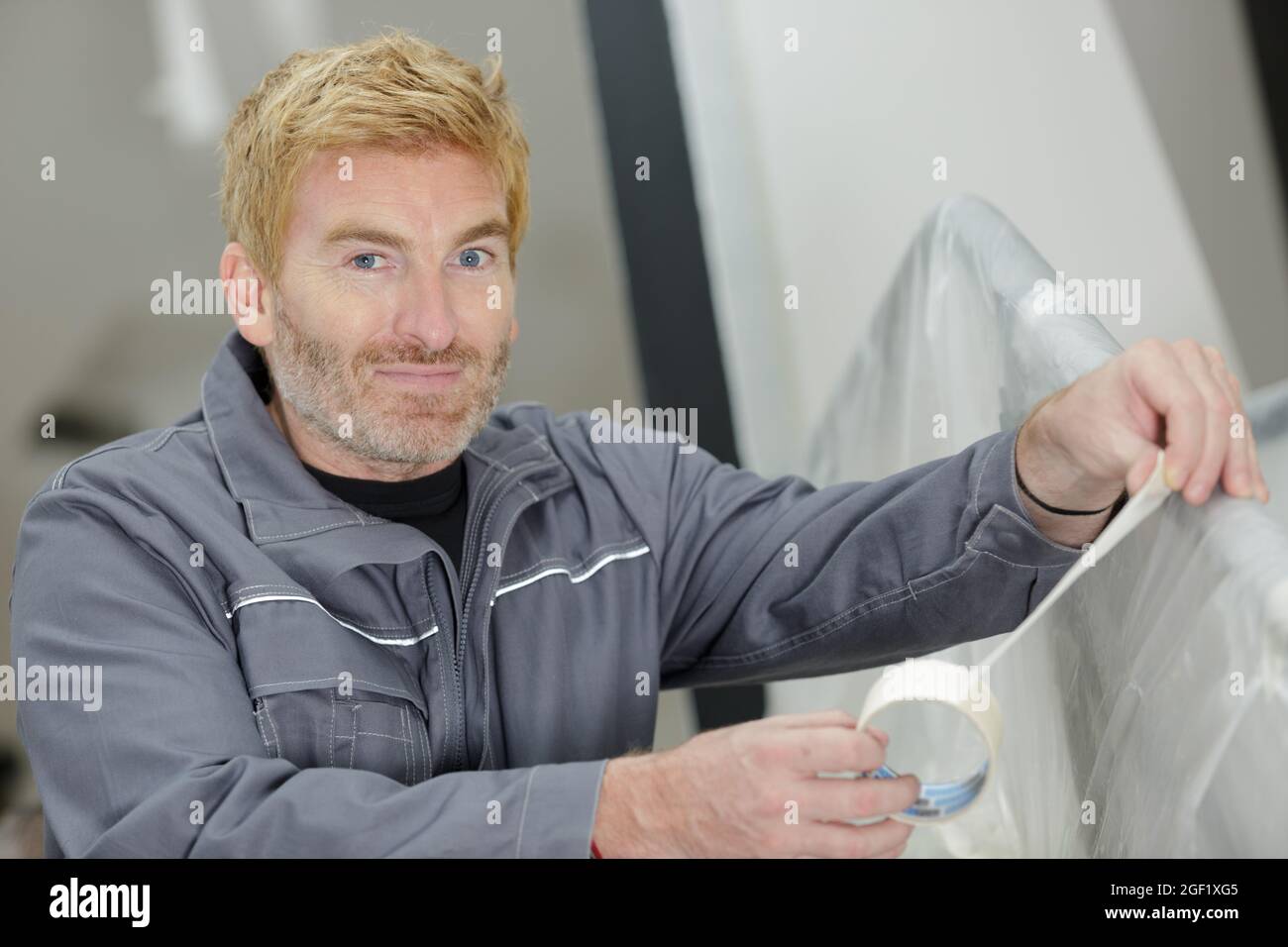 worker protecting batten moulding with masking tape Stock Photo - Alamy