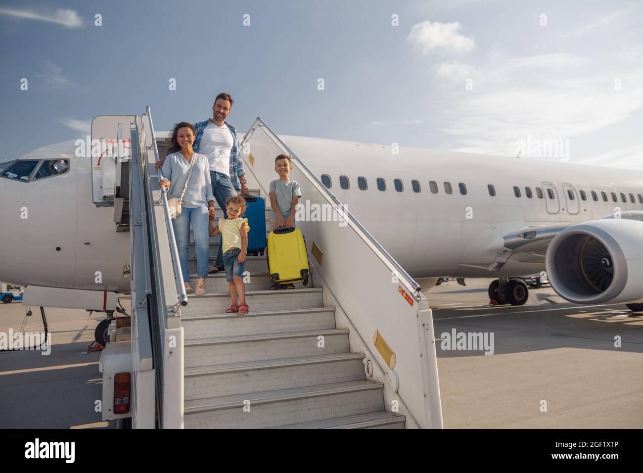 Happy family of four getting off the plane on a daytime Stock Photo - Alamy