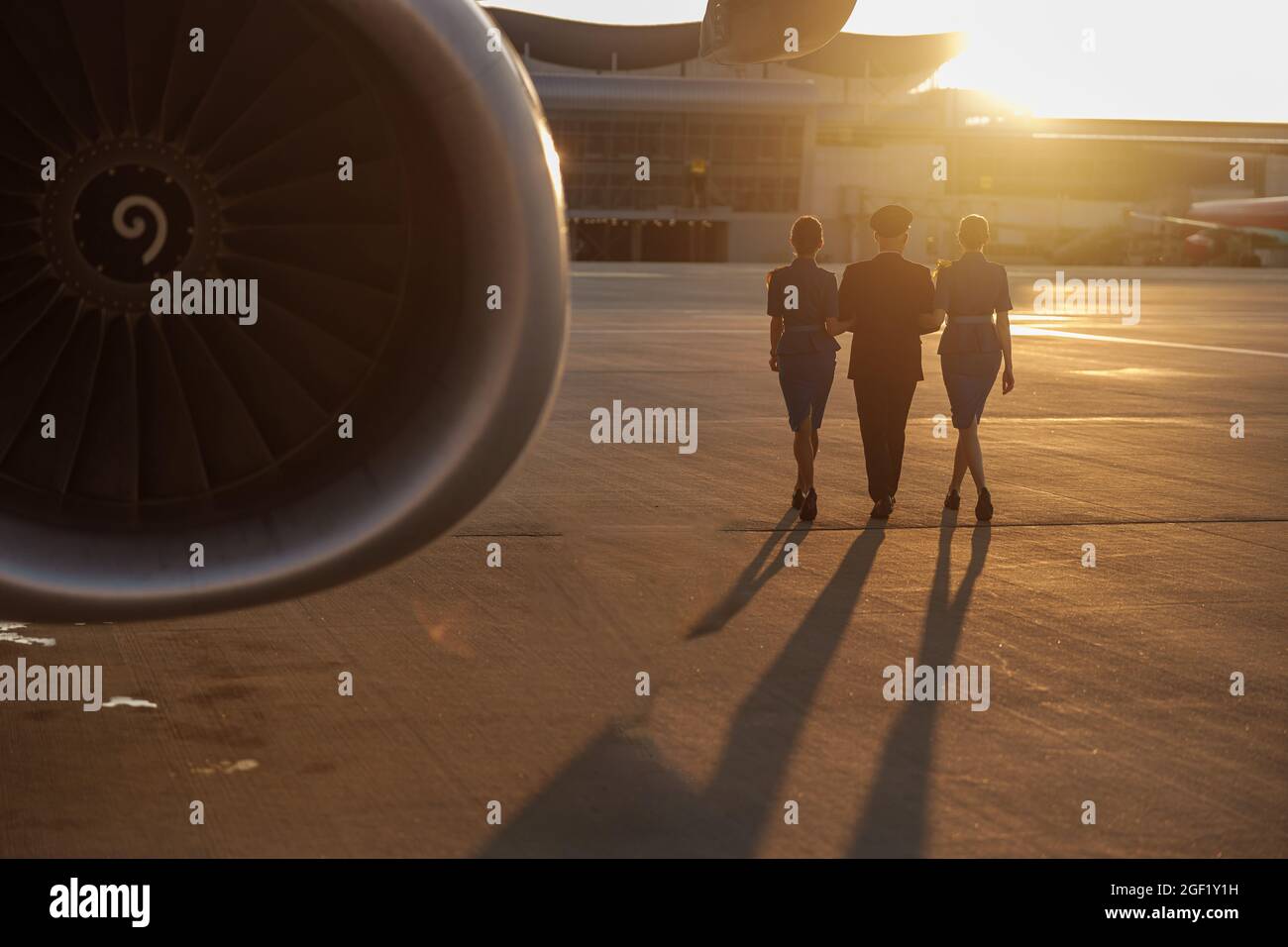 Full length shot of professional pilot walking together with two female ...