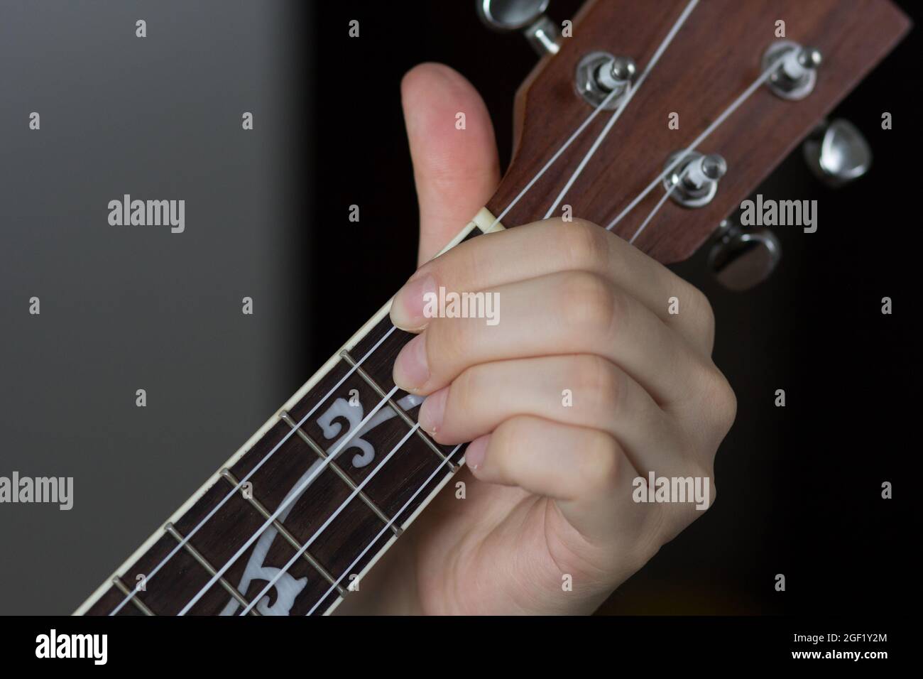 Woman hand playing ukulele on black background Stock Photo - Alamy