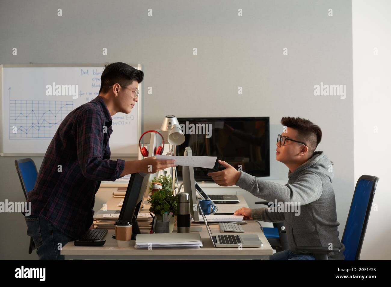 College student passing document to his friends when they are working ...