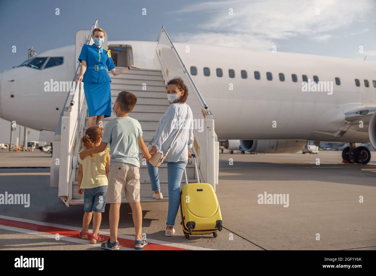 Back view of mother with two little kids wearing protective mask ...