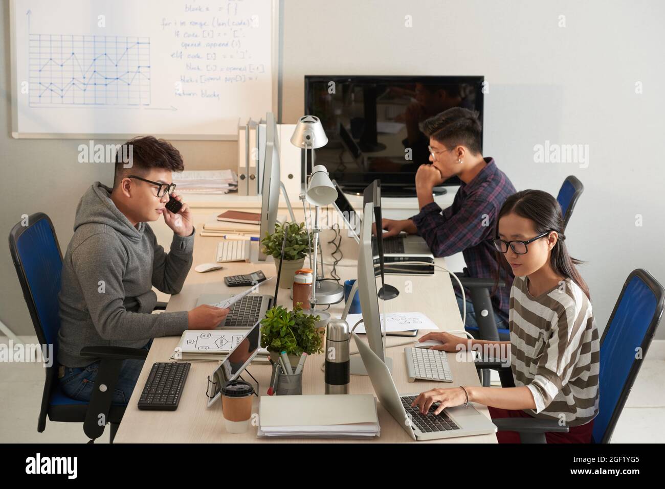Software testing department working on computers at big office table ...