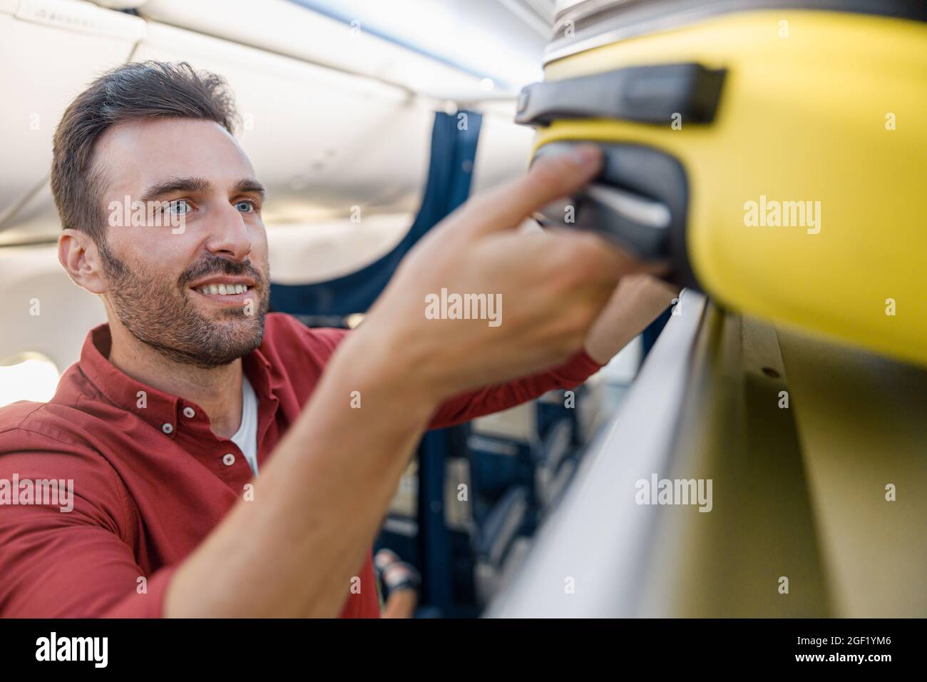 Portrait of cheerful man pulling out suitcase from hand luggage ...
