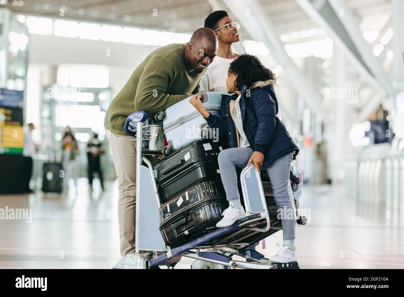 African family with luggage trolley waiting at airport terminal for ...