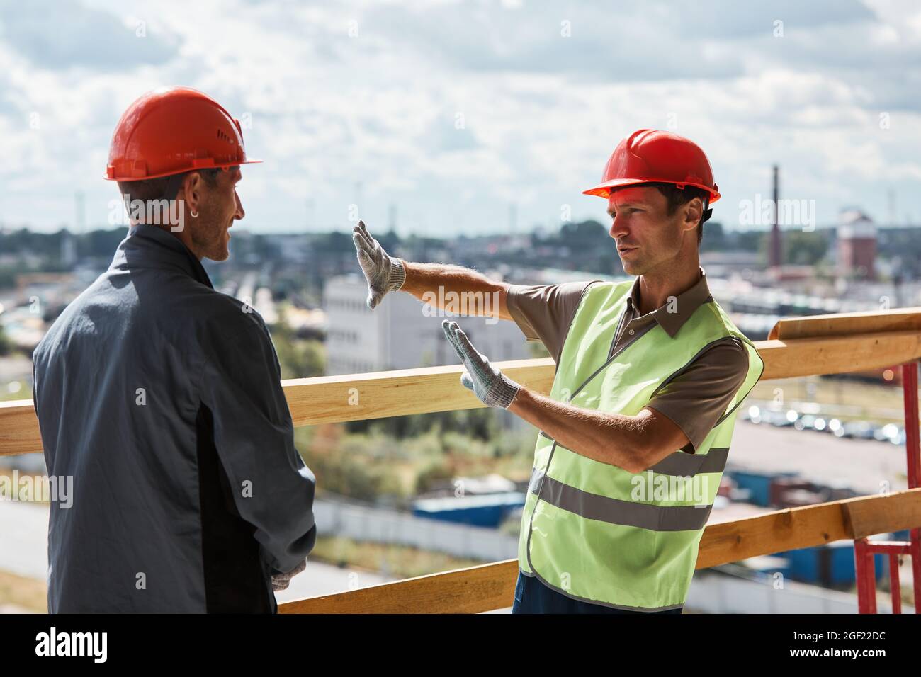Portrait of two construction workers discussing project while standing ...