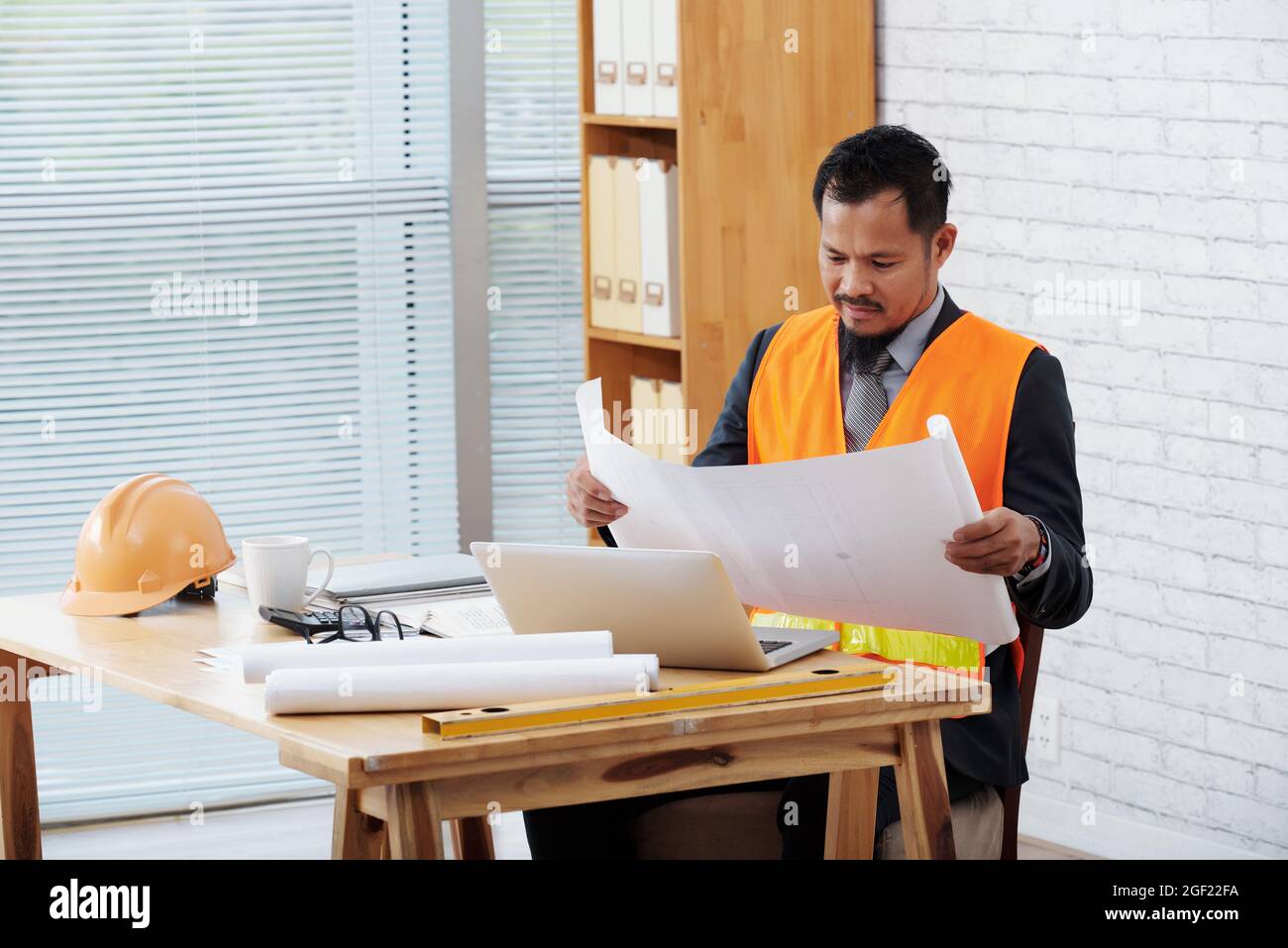 Head contractor working with documents, he is rolling out construction ...