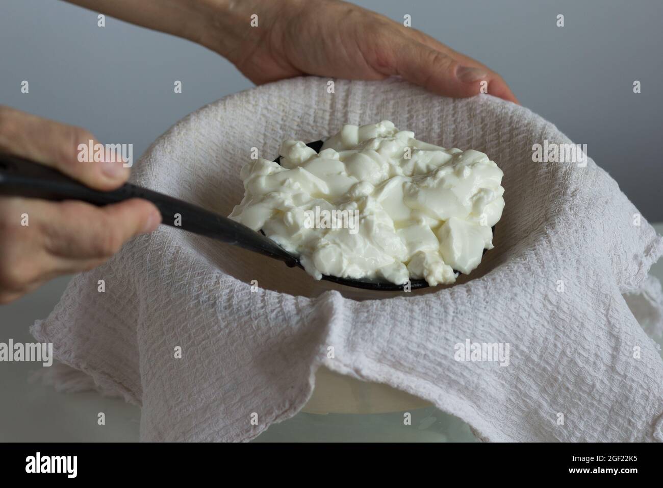 Woman hands putting mess of fermented cheese or cottage cheese or greek ...