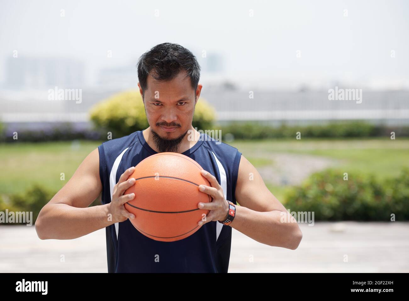 Portrait of determined basketball player squeezing ball and looking at ...