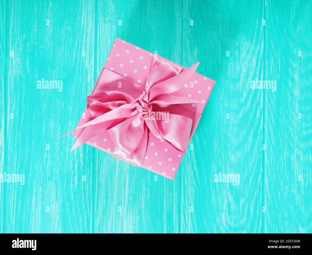One gift box with a pink bow on a wooden background, copy of the text ...