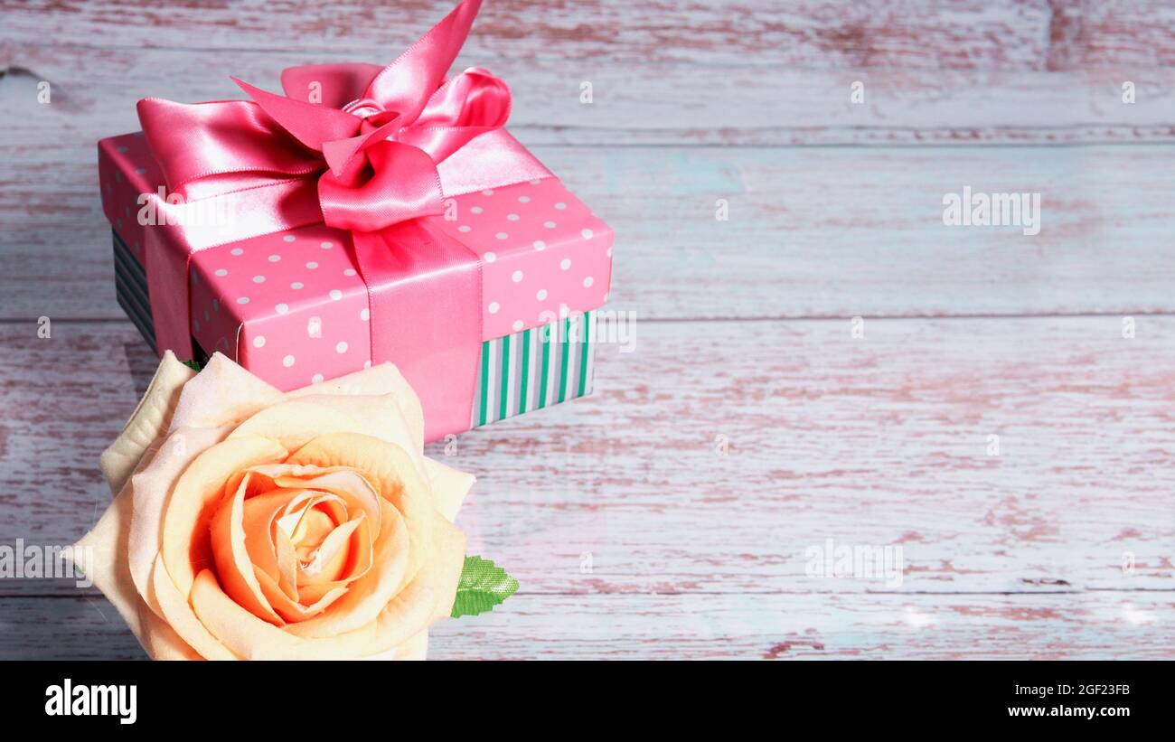 One gift box with a pink bow on a wooden background, copy of the text ...
