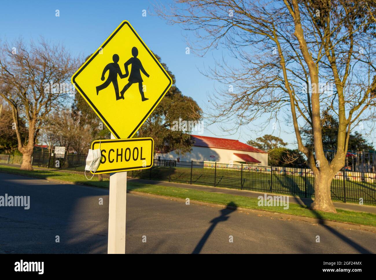 White face mask on a road school sign sybolising that Covert-19 effects ...