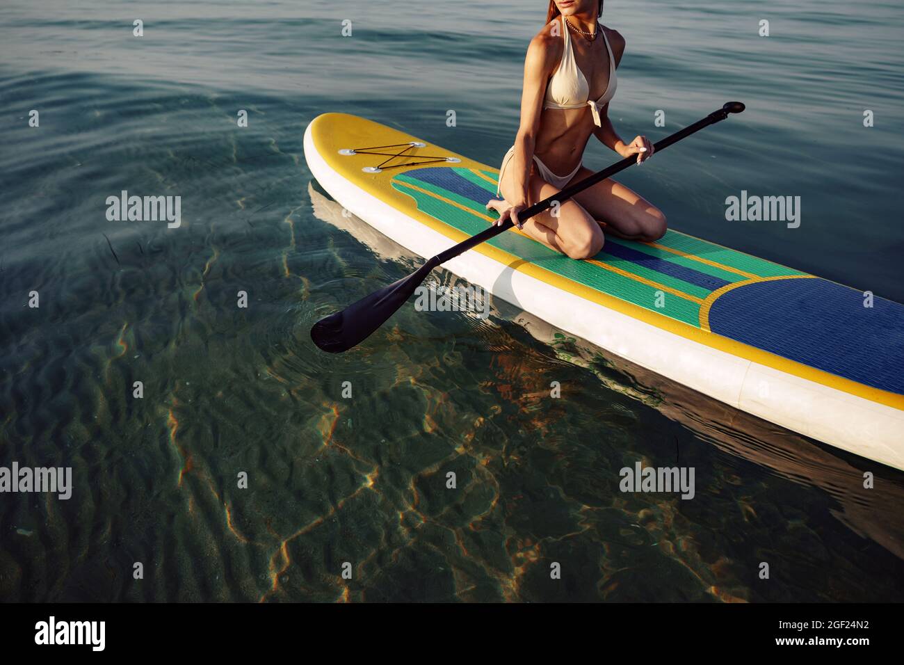 Close up of young woman sitting on a stand up paddle board Stock Photo ...