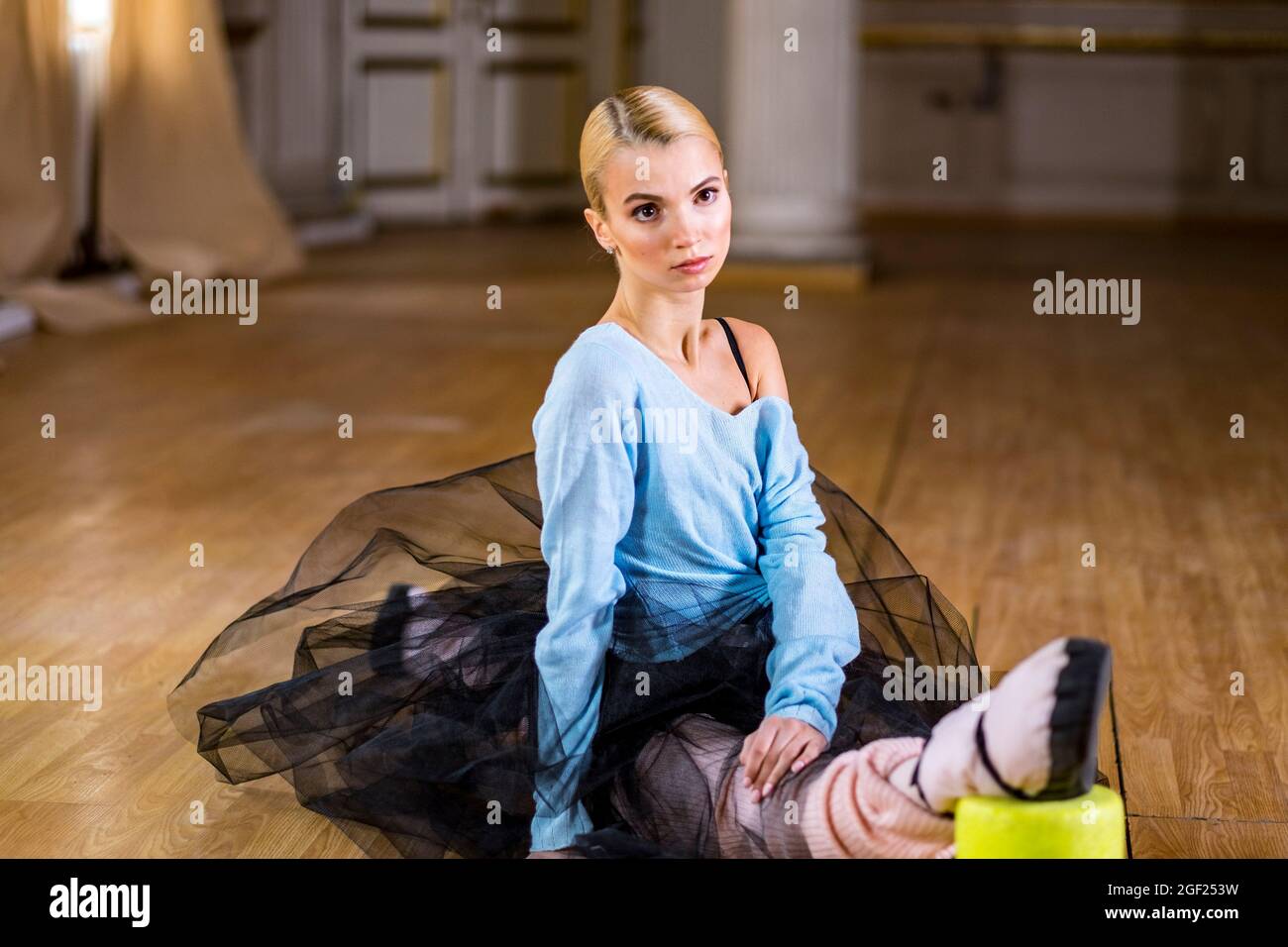 Female ballet dancer performs stretching exercises before beginning a ...