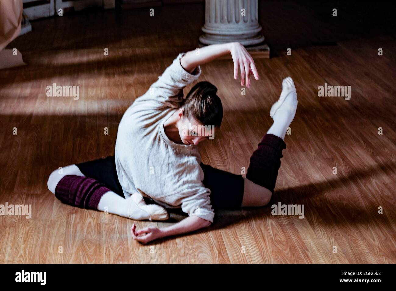 A young ballerina stretches in advance of a dance rehearsal in a ...