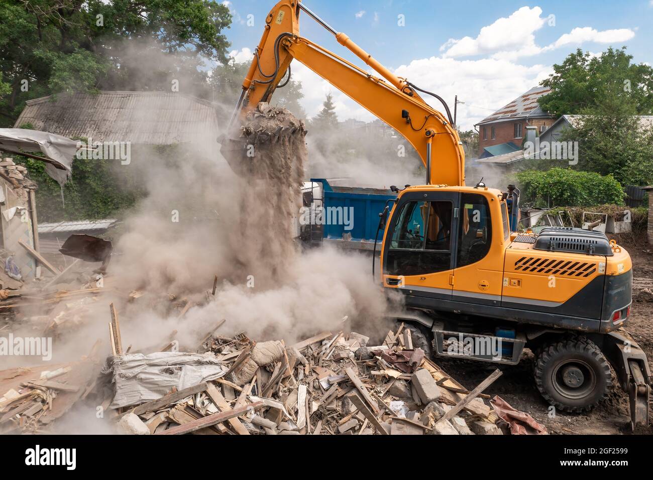 Demolition of building by industrial excavator. Bucket breaks walls and ...