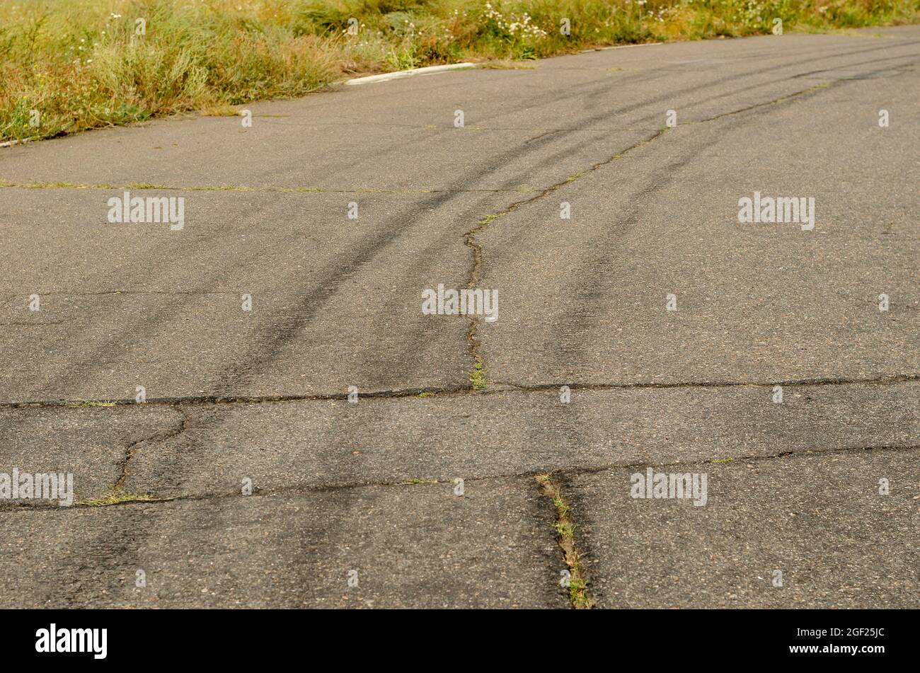 Gray asphalt with black tire tracks. An old country road with cracks ...
