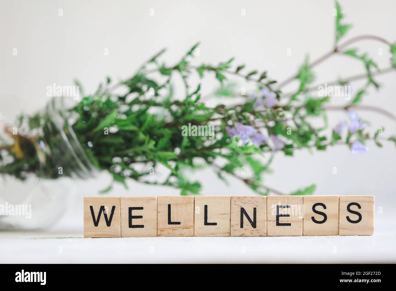 WELLNESS text in wooden block letters with bunch of fresh flowers in ...