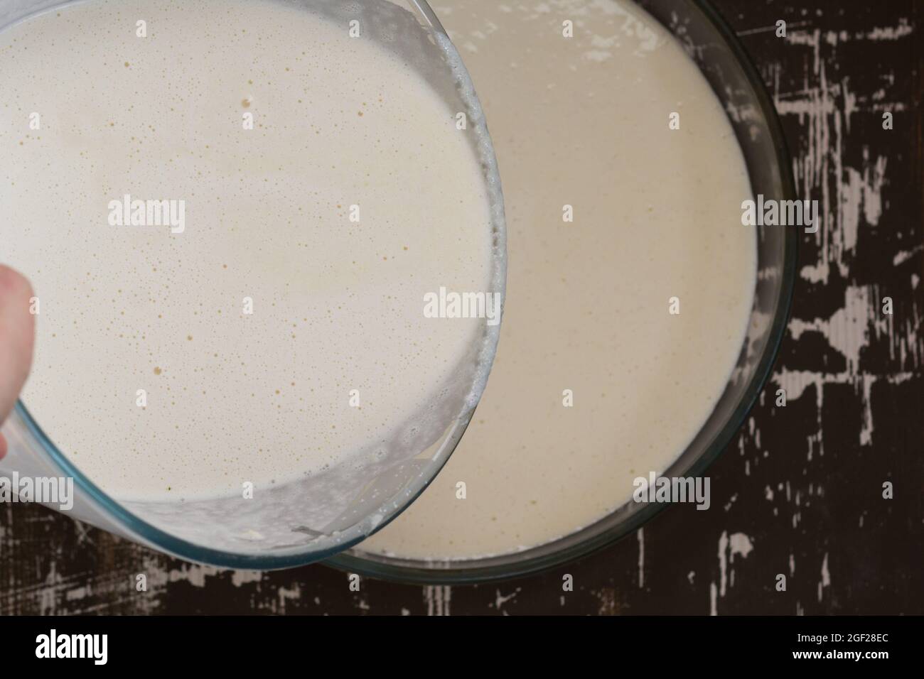 Top view of woman hand pouring semolina batter into form for baking ...