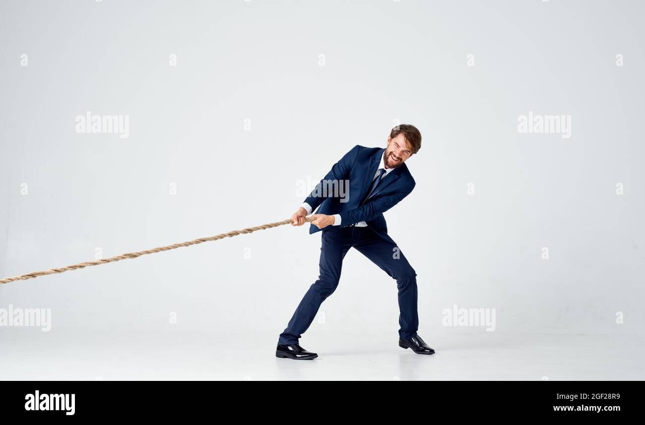 a man in a suit pulling a rope office manager teamwork Stock Photo - Alamy