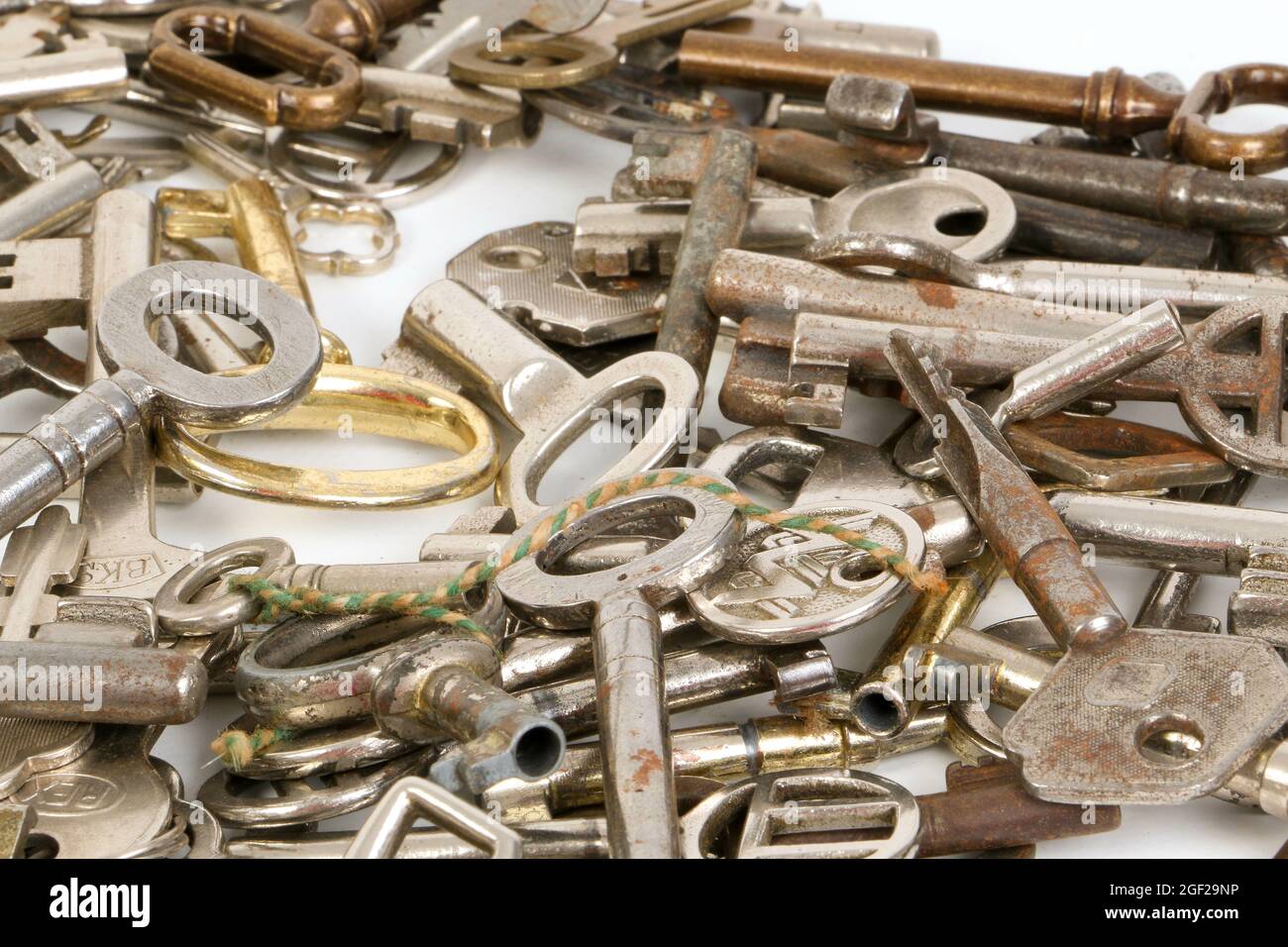 Closeup of a pile of old used rusty metal keys on the white surface ...