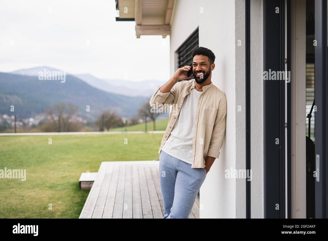 Young man student with smartphone outdoors on patio at home, making a ...