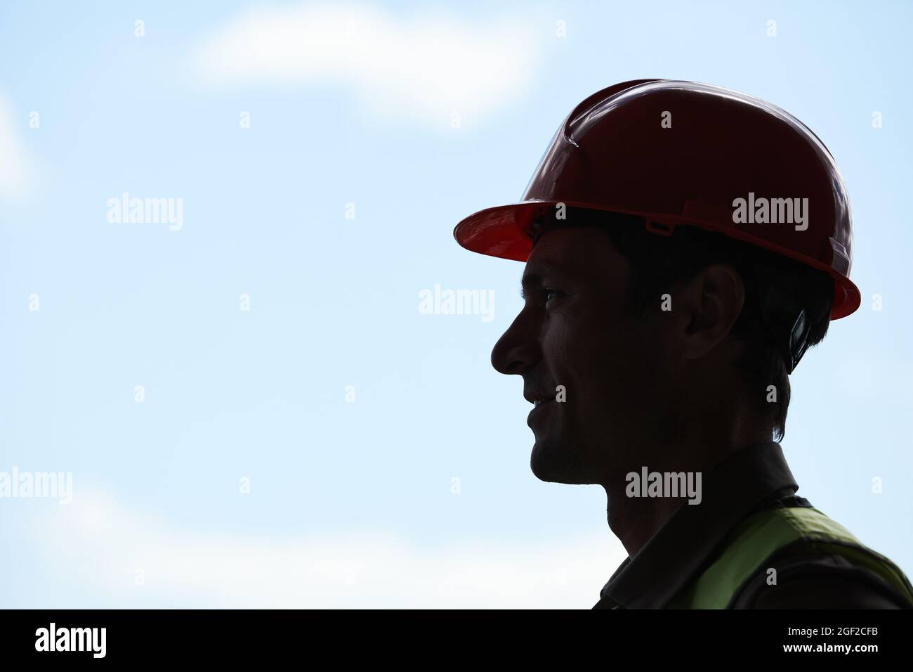 Backlit side view portrait of male construction worker wearing hardhat ...
