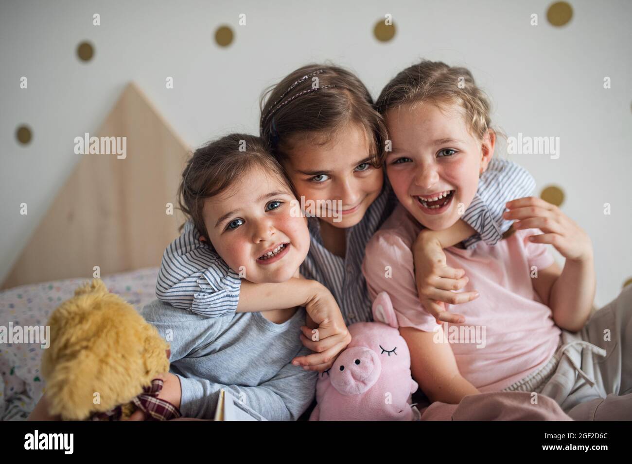 Portrait of three girls sisters indoors at home, looking at camera ...