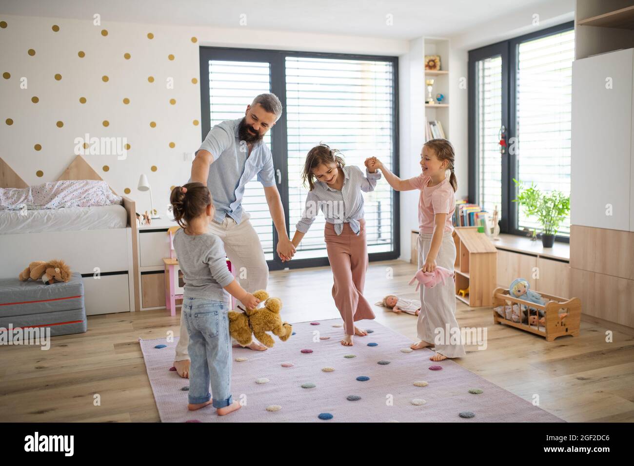Father With Three Daughters Indoors At Home Playing And Holding Hands