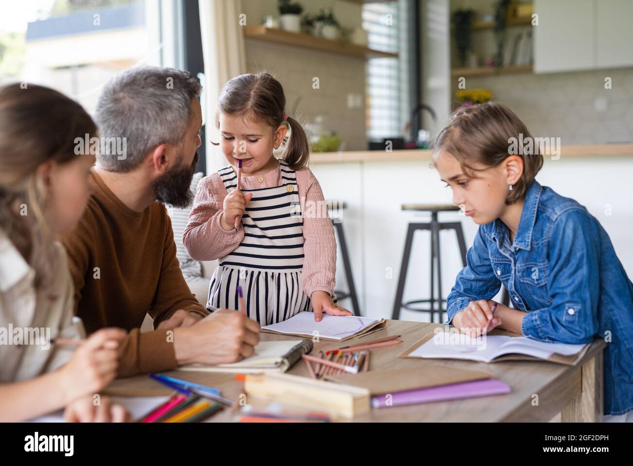 Father With Three Daughters Indoors At Home Drawing Pictures Stock