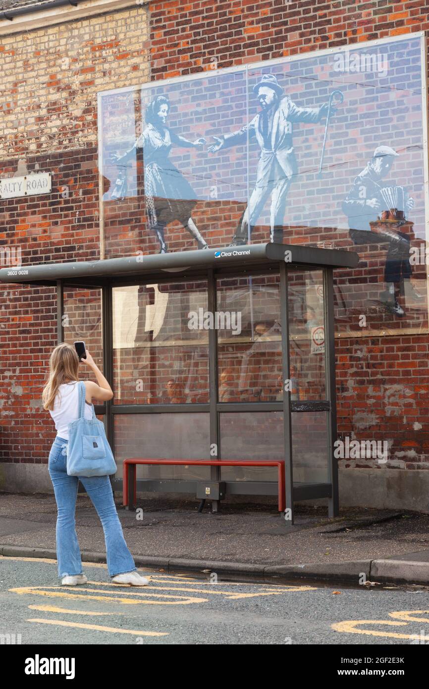 People gathering to look at Banksy's Dancers street art at a bus stop ...