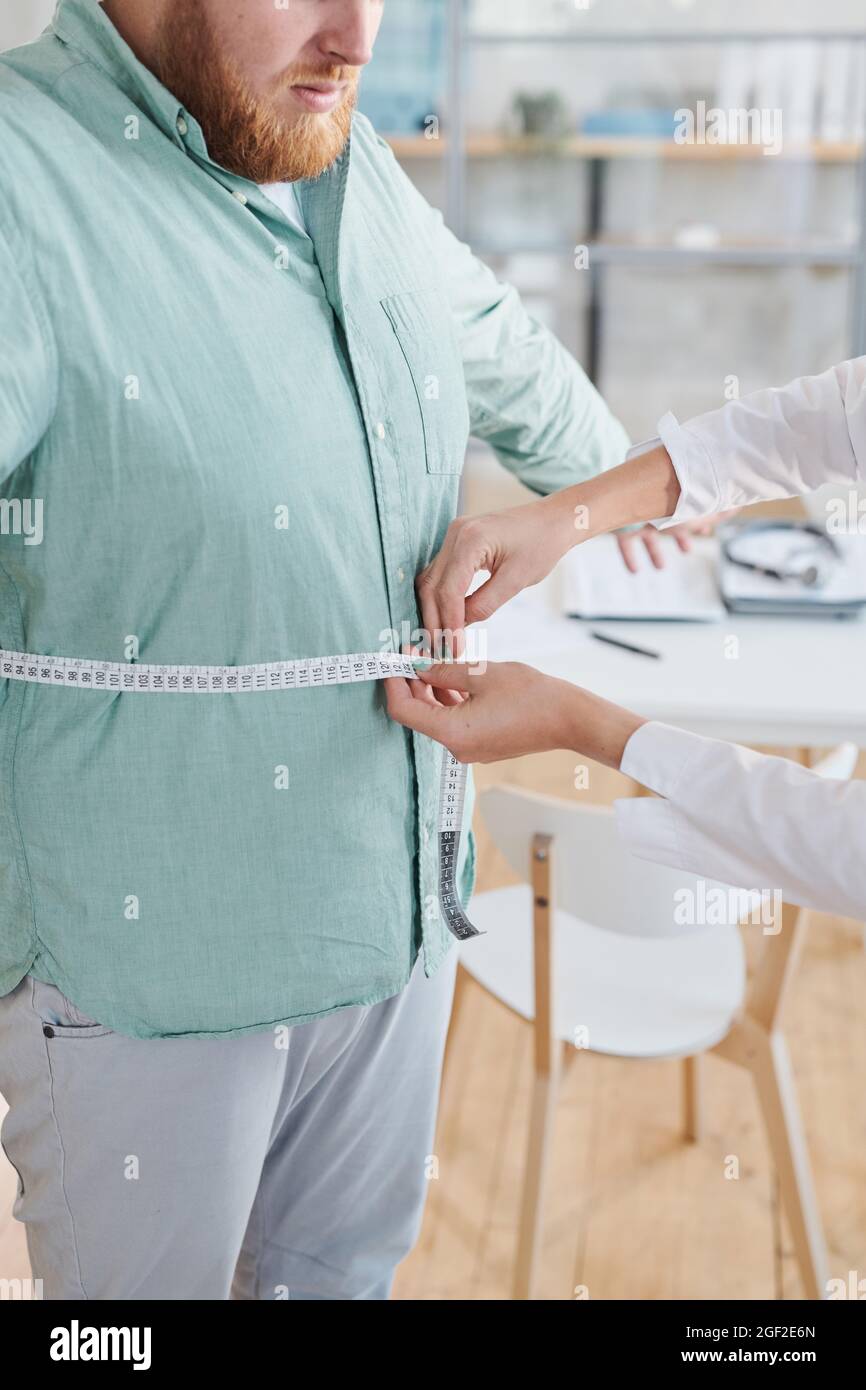Close-up of nutritionist measuring the waist of her patient with tape ...