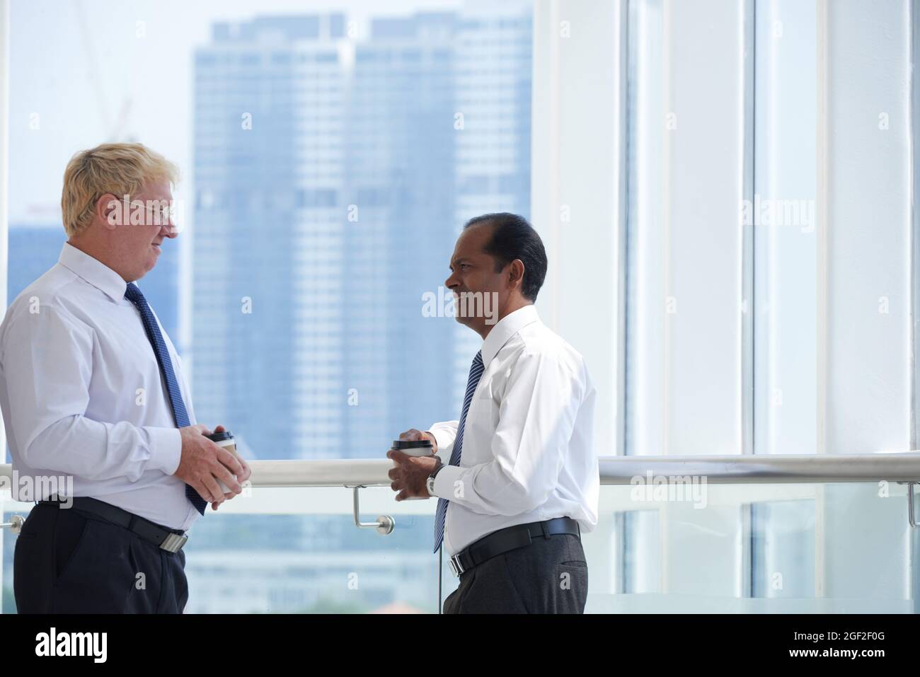 International business partners having meeting on office balcony ...