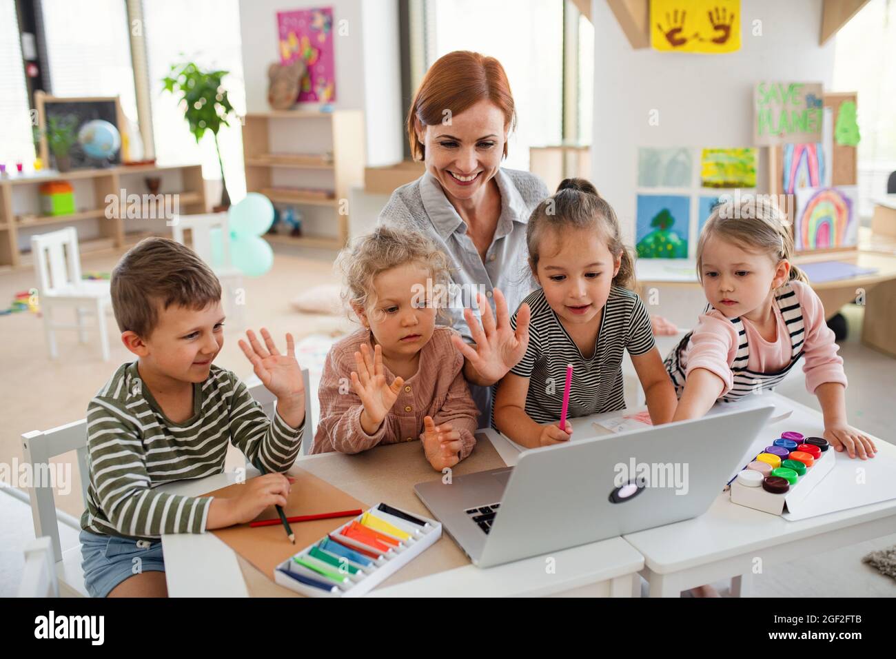 Group of small nursery school children with teacher indoors in ...
