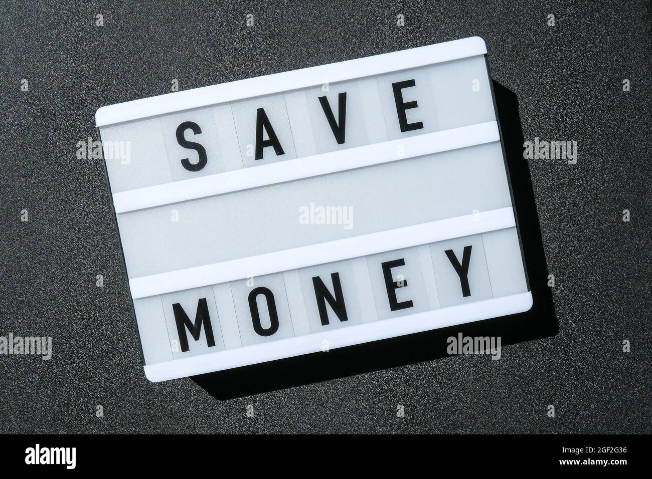 Lightbox board on a black background with the words SAVE MONEY in black ...