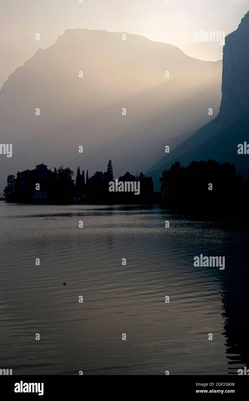 A medieval castle on an alpine lake in northern Italy, silhouetted by ...