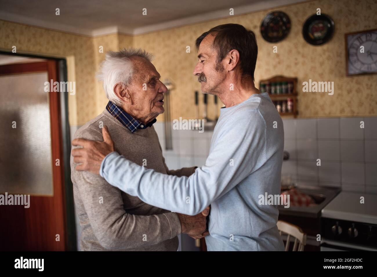 Portrait of man with elderly father indoors at home, shaking hands ...