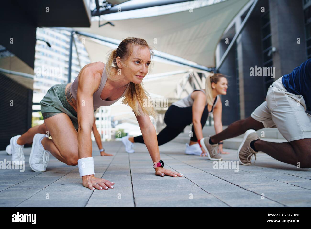 Group of young people doing exercise outdoors in city, healthy ...