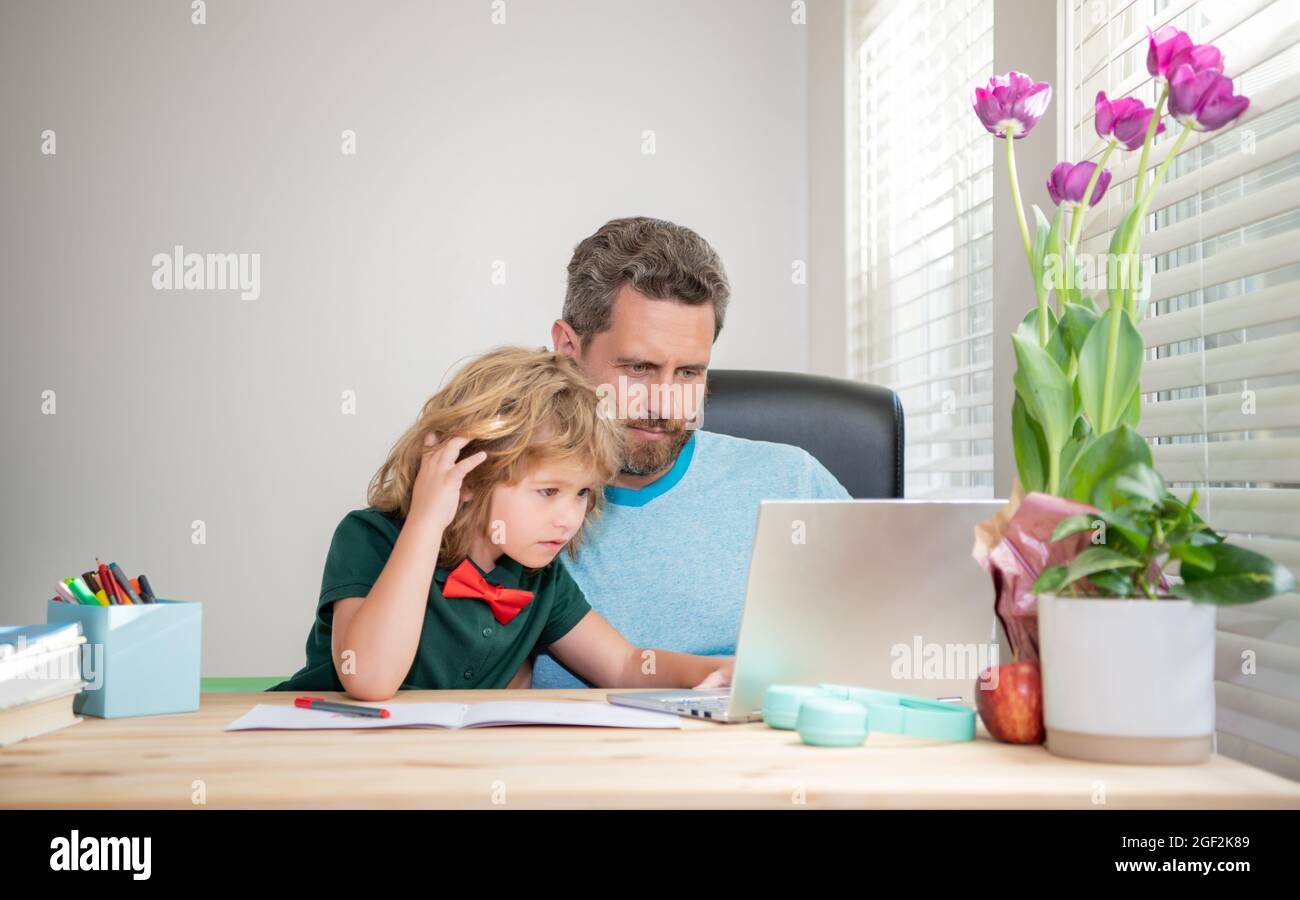 back to school. comcentrated father and son use computer at home ...