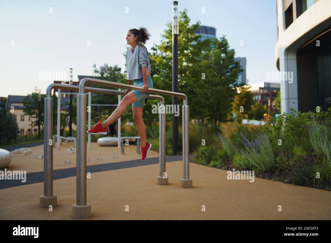 Mid adult woman doing exercise on parallel bars outdoors in city ...