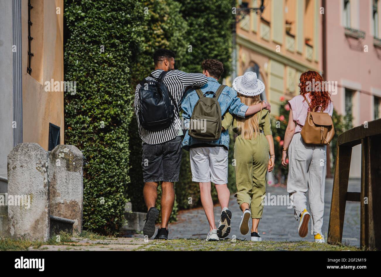 Rear view of group of happy young people outdoors on trip in town ...