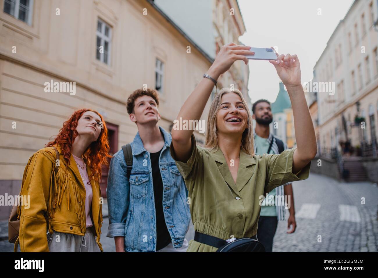 Group of young people sightseeing outdoors on trip in town, taking ...