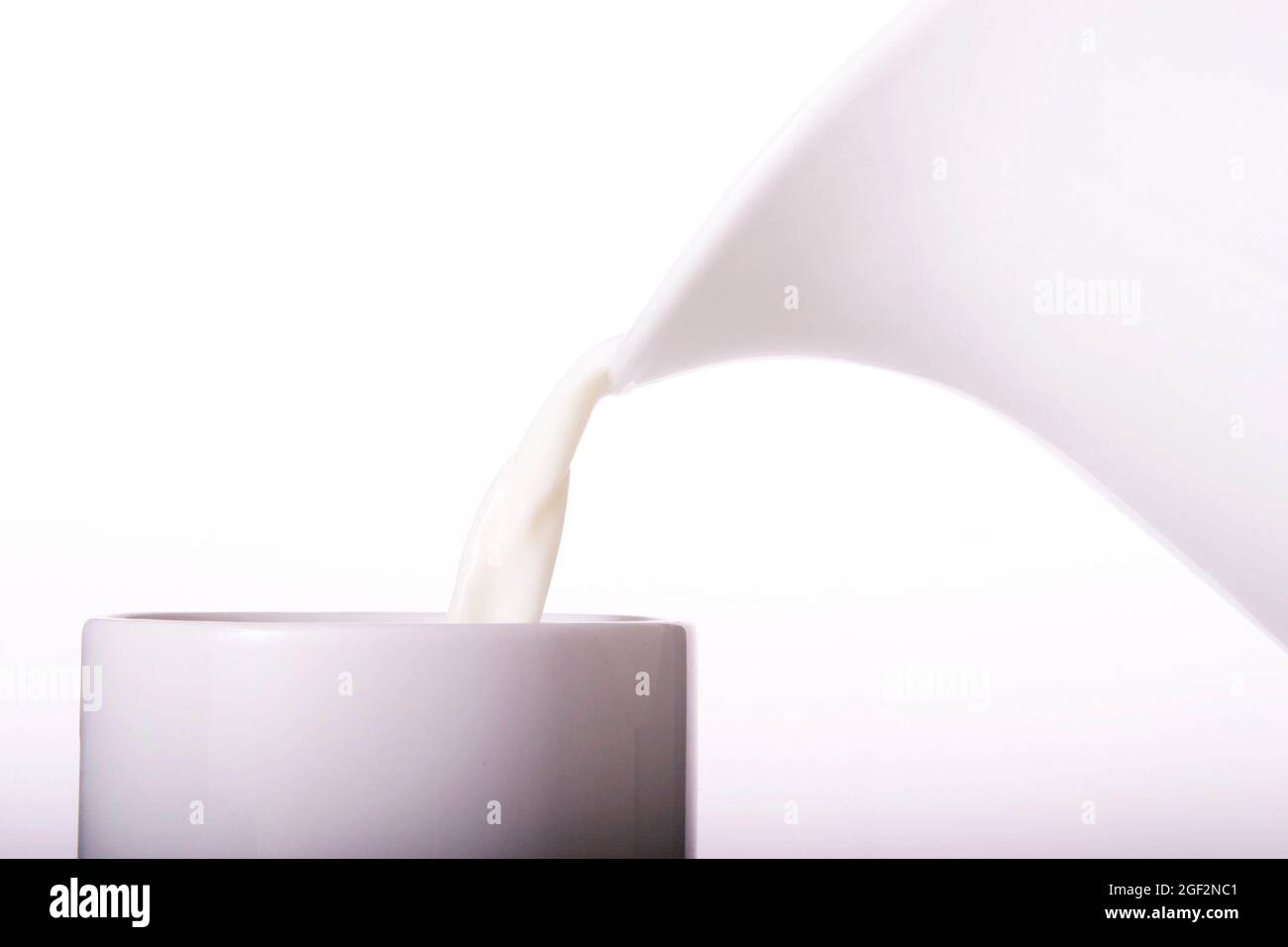 pouring milk from a pitcher into a cup Stock Photo - Alamy